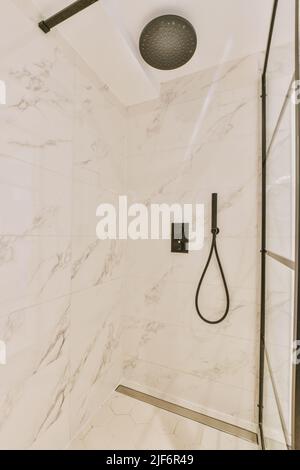 Shower faucets attached to tiled wall near glass partition and ...