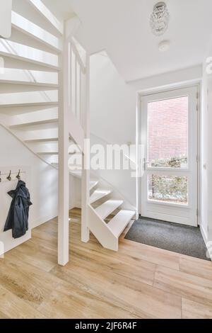 White hallway with wooden stairway leading to second floor of modern ...