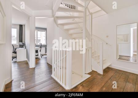 White hallway with wooden stairway leading to second floor of modern ...