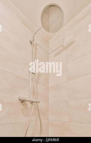 Shower faucets attached to tiled wall near glass partition and ...