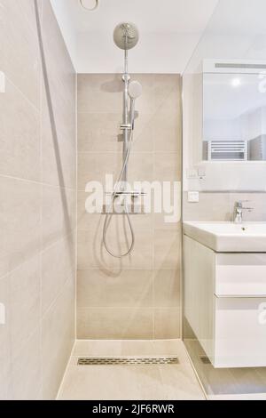 Shower faucets attached to tiled wall near glass partition and ...