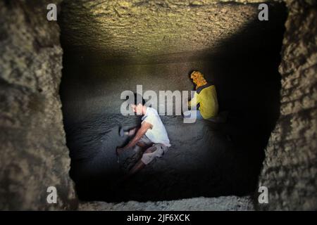 Workers digging and carving through rock to build a chamber for ...