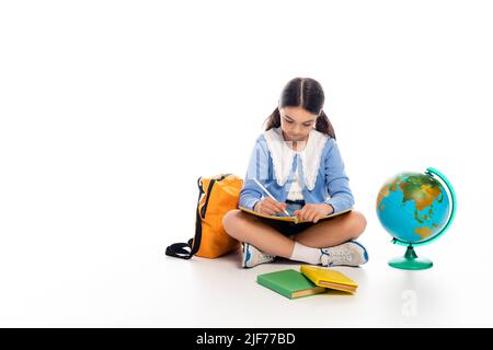 Preteen schoolkid writing on notebook with sticky note near laptop and ...