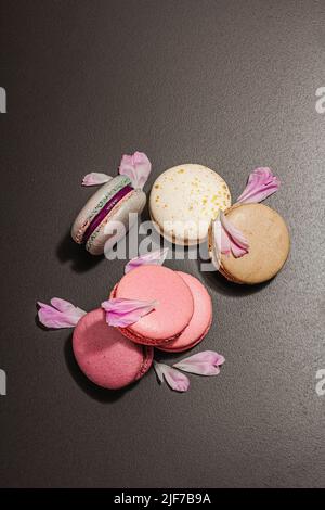 Macarons with peony flower on a black stone background. Sweet dessert ...