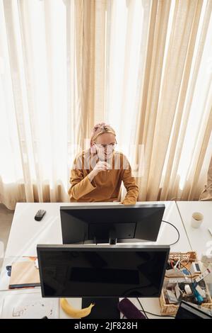 High angle view of programmers sitting at table with computer monitors ...