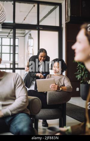 Biracial mid adult businesswoman discussing with colleague during ...