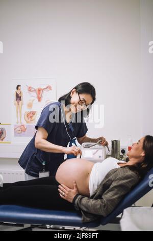 Pregnant woman lying on examination table while doctor performs an ...