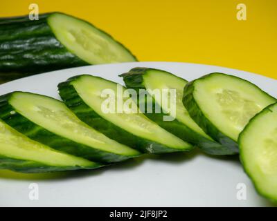 A smooth, medium-sized cucumber on white plate, sliced. Cucumber on a ...