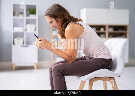 Woman With Neck Pain Sitting Using Mobile Phone Stock Photo - Alamy