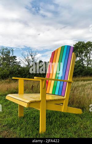Yellow wooden chair, back painted in rainbow colours, standing in a ...