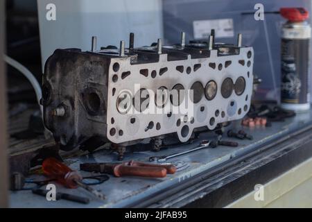 Old cylinder head of a 8V diesel engine sitting on a bench or atable ...