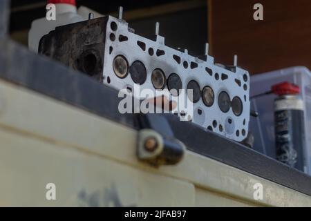 Old cylinder head of a 8V diesel engine sitting on a bench or atable ...