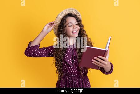 cheerful child with frizz hair recite book on yellow background Stock ...