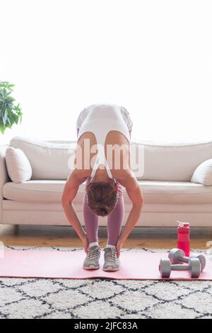 Beautiful sportswoman doing exercises indoors in gym, lying on mat ...