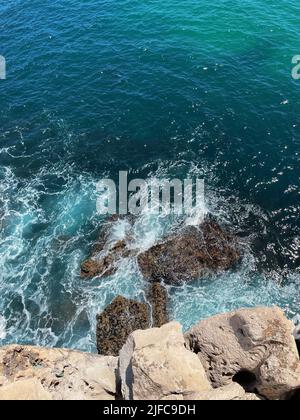 A vertical shot of rocks in the ocean under a blue sky Stock Photo - Alamy