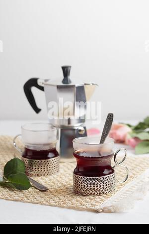 Cups of fresh coffee and a classic coffee maker on white table Stock ...