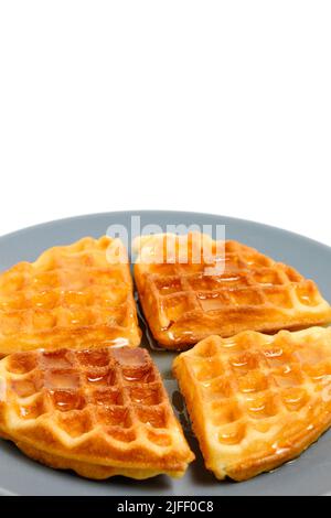 Soft muffin waffles poured with fresh honey using honey spoon, in plate ...