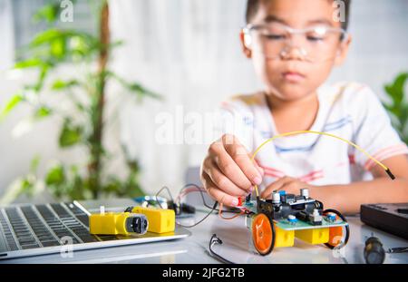 Asian kid boy plugging energy and signal cable to sensor chip with ...