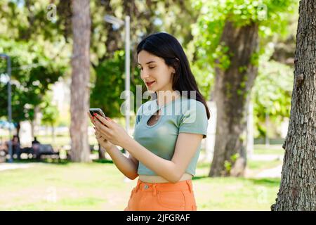 Cute caucasian woman wearing turquoise tee on city park, outdoors ...