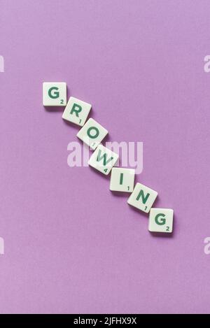 Growing formed of scrabble blocks on lilac background Stock Photo - Alamy