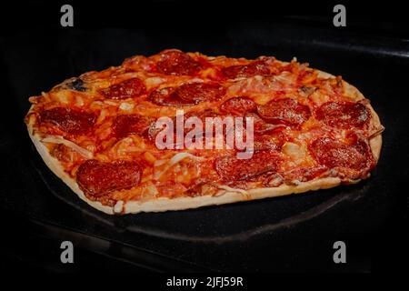 Burnt homemade pizza on tray in electric oven, black background Stock ...