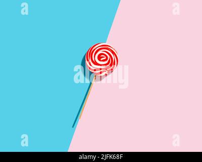 Red and white colored swirl round candy lollipop on blue textured ...