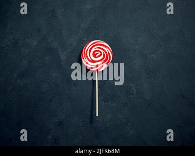 Red and white colored swirl round candy lollipop on pink and blue ...