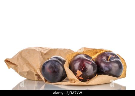 Three dark blue organic plums with a package of paper, close-up ...