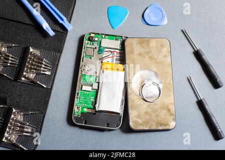 Disassembled mobile phone with technician tools on color background ...