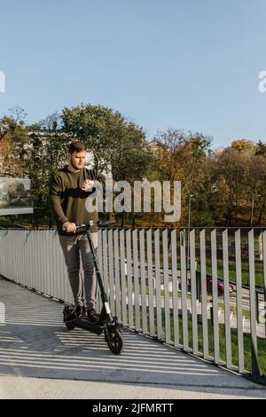 young strong man riding electric kick scooter copy space Stock Photo ...