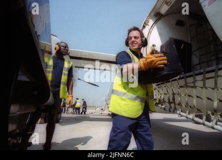 Airport luggage handlers unloading and transporting airline passengers ...