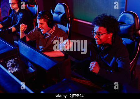 Smiling gamer with headphones celebrating win game by showing victory ...