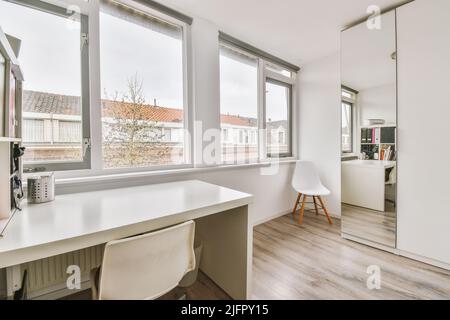 Comfortable chair placed near table with computer monitors in light ...