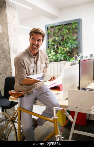 Young confident IT engineer or software developer in casualwear sitting ...