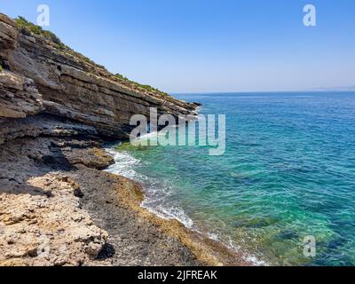 A cliff in the greenish blue sea against the background of the sky ...