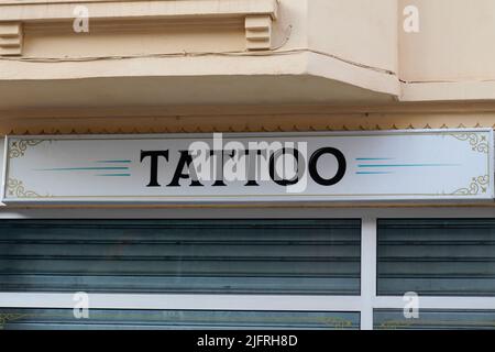 Tattoo text sign in letters white on facade wall shop entrance in the ...