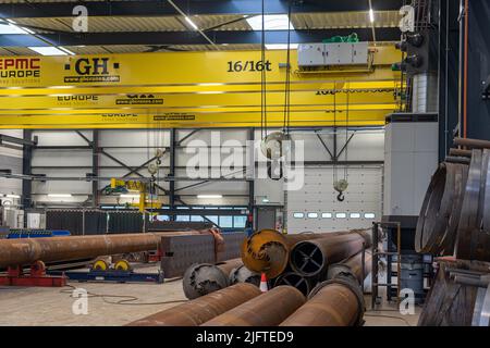 Interior of a steel factory with mobile cranes, steel piles and beams ...