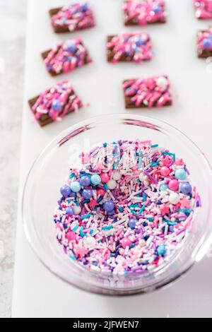 Drizzling melted pink chocolate on top of the mini chocolates and ...