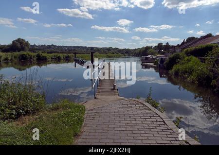 Small wodden pier with still water and refection of clouds on the river ...