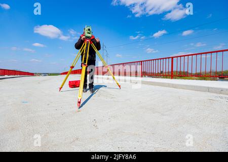 Surveyor engineer is measuring bridge under construction, site ...