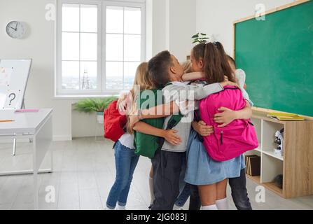 Group of little school friends hug each other tightly as they arrive at ...