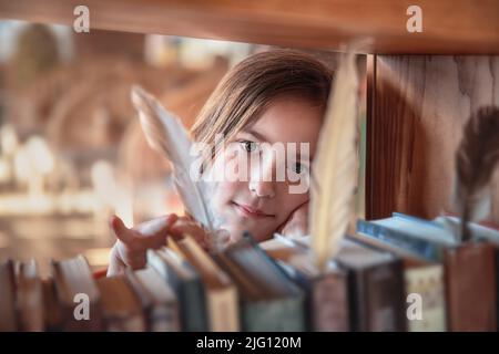 a cute girl stands behind a shelf with books Stock Photo - Alamy