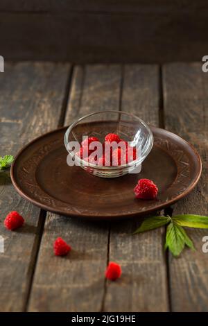 Aromatic raspberry tea in glass cup and berries on wooden table against ...