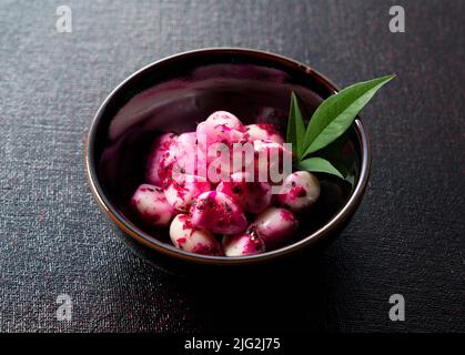 Pickled shiso bonito garlic on a plate placed on a black background ...