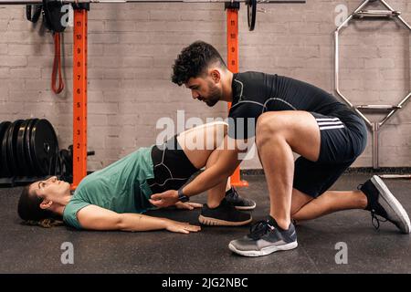 Personal trainer with a first-time trainee correcting habits in the ...