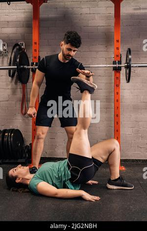 Personal trainer with a first-time trainee correcting habits in the ...