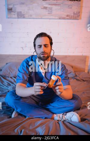 Young sleepwalker in doctor uniform holding pen and clipboard while ...