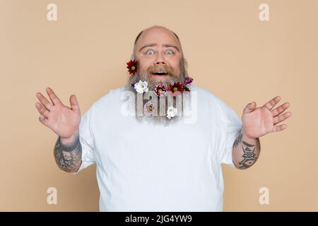 amazed overweight man with beard and tattoos holding hands near face ...