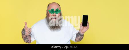 bearded overweight man in clover-shaped glasses talking on smartphone ...