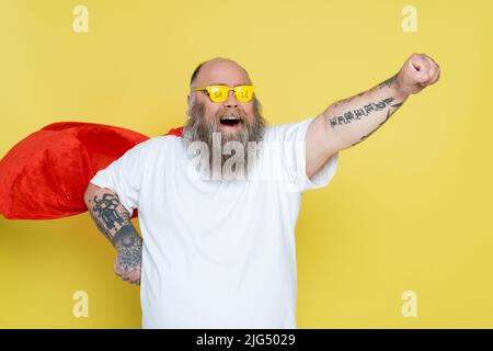 thrilled overweight man in red sunglasses and superhero cloak using ...